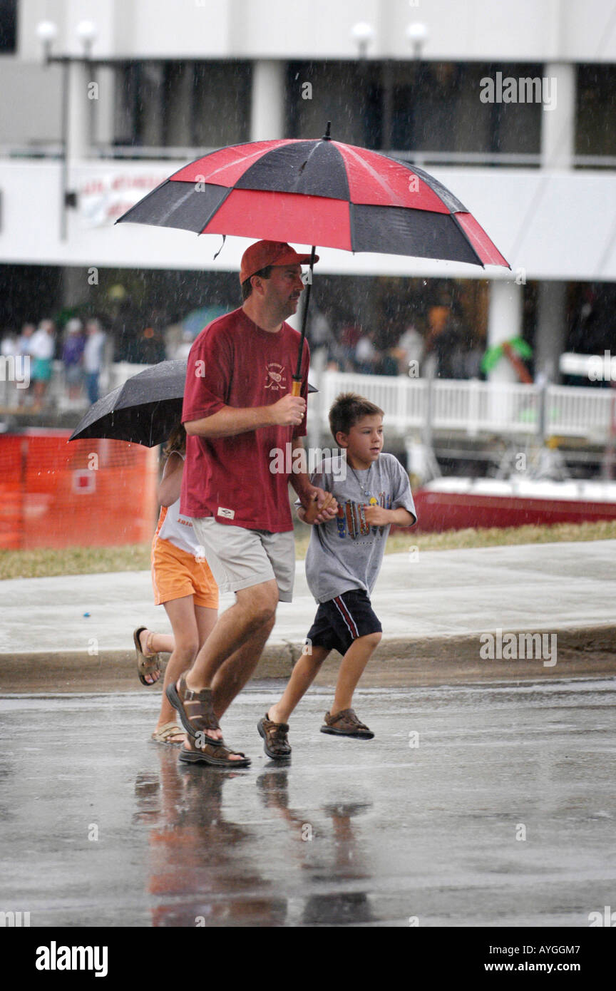 Pedestrian with umbrella protection is caught in rain storm on a public ...