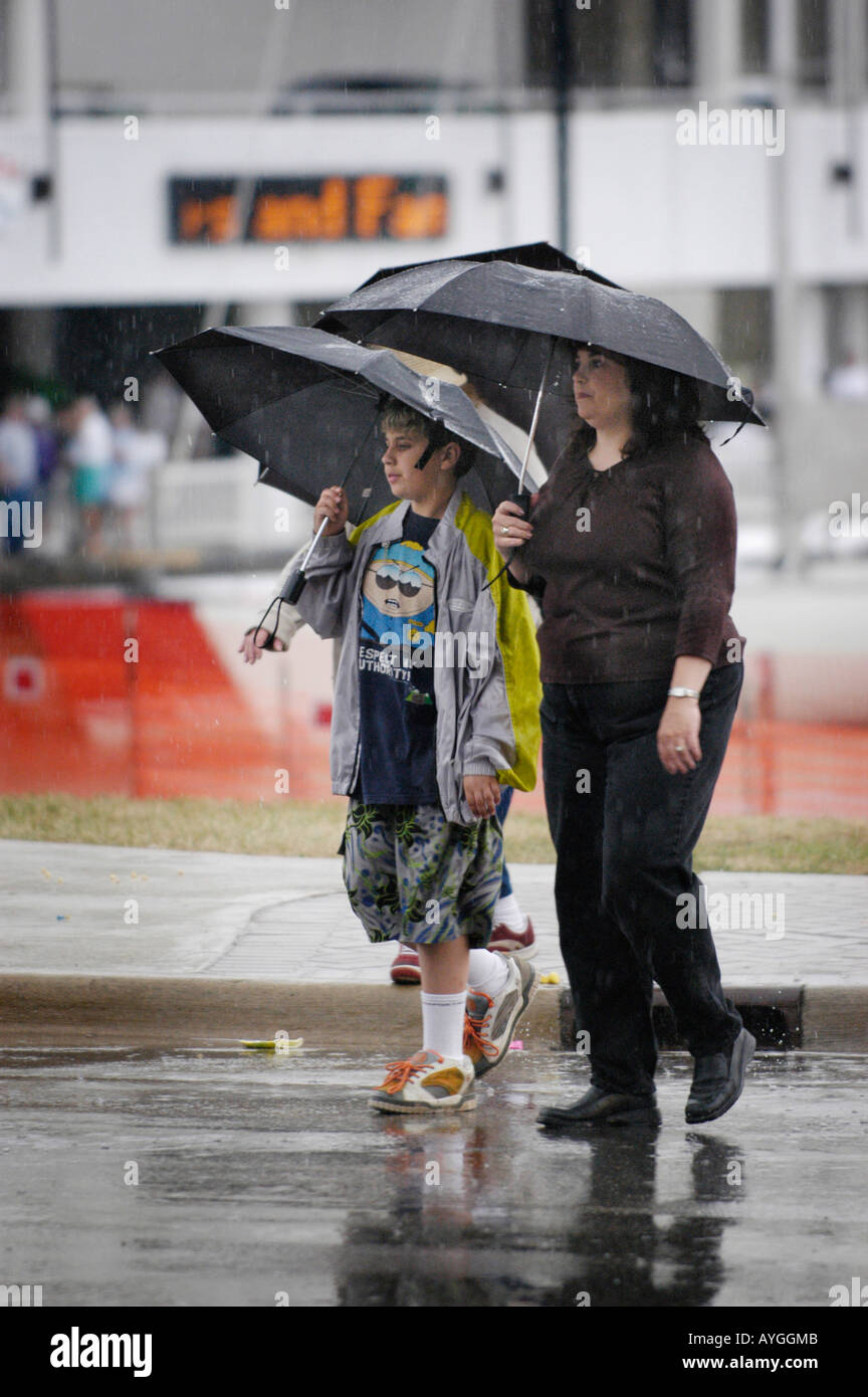 Pedestrian with umbrella protection is caught in rain storm on a public ...