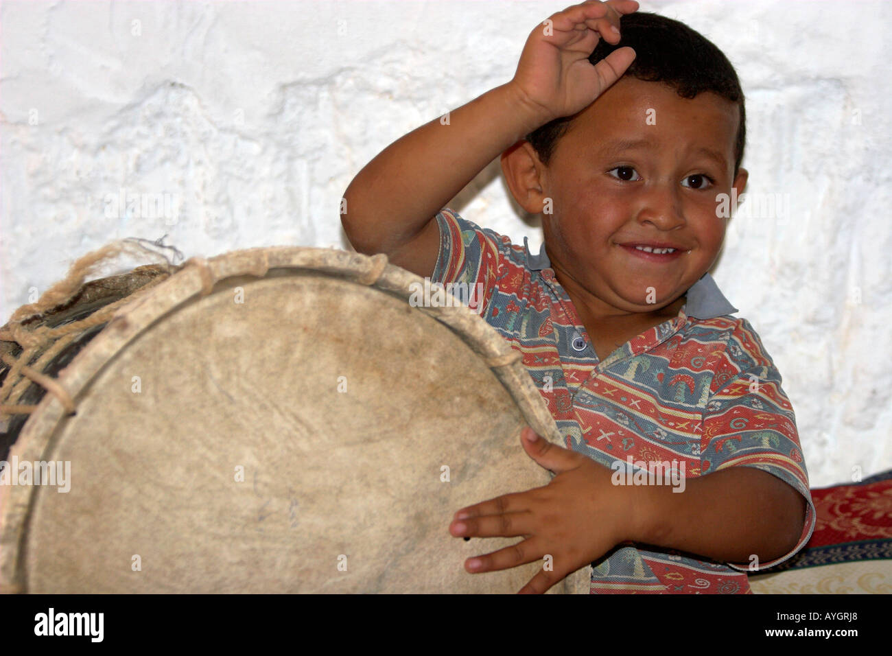 Mischievous boy beats drum with hands in underground Berber family home ...