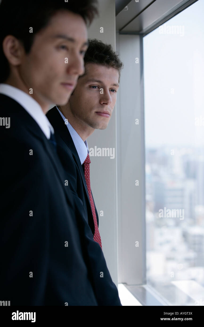 Two businessmen looking through window Stock Photo - Alamy