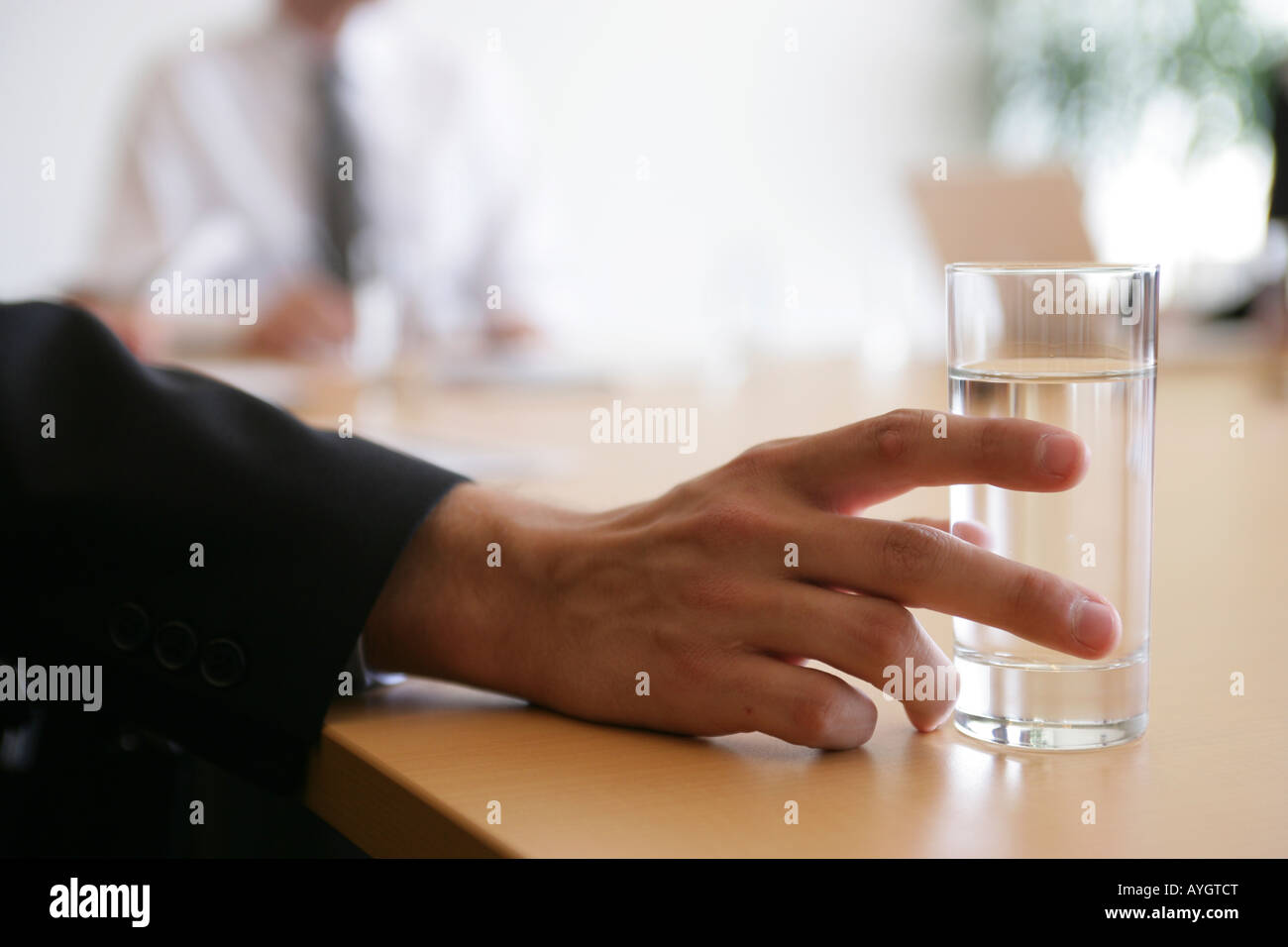 Hand reaching glass of water on table in conference room, close-up ...