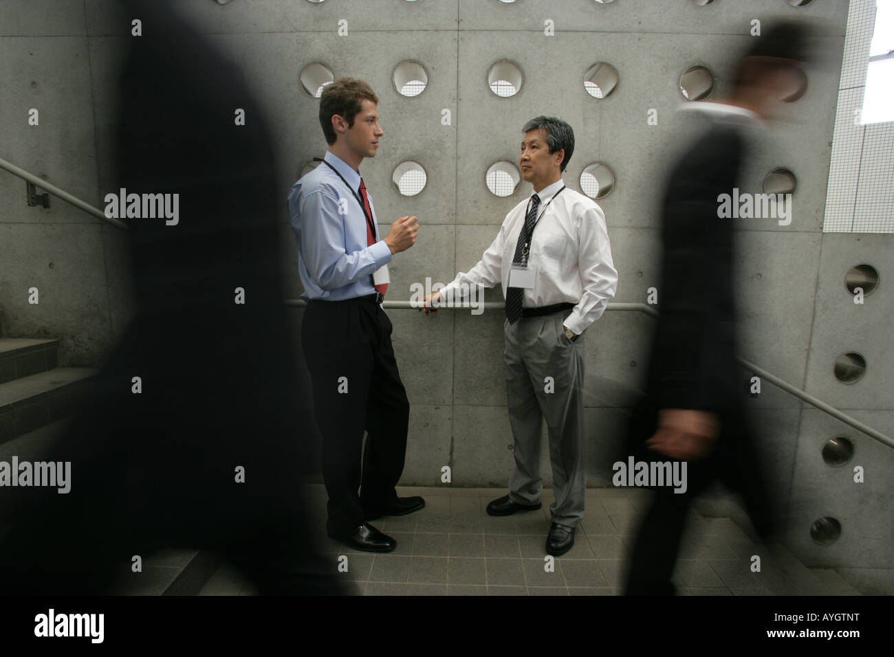 Two business men talking standing on busy office staircase Stock Photo ...
