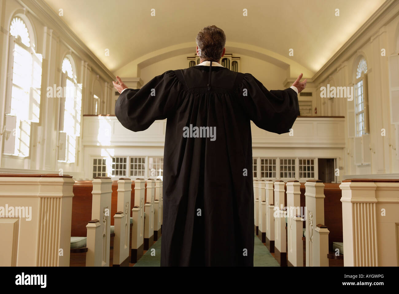 Priest with arms raised in church Stock Photo - Alamy