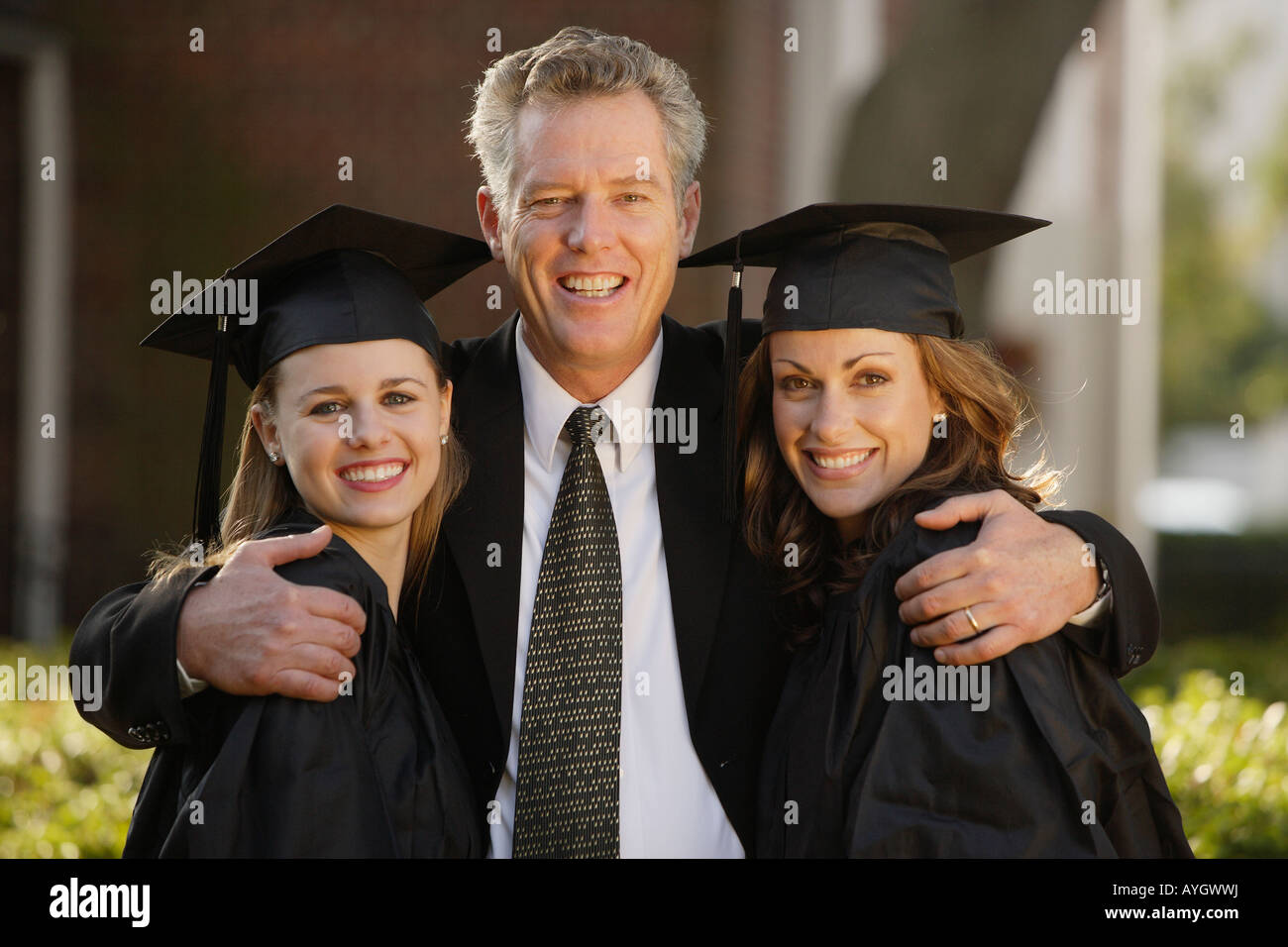 Father hugging graduate daughters Stock Photo - Alamy