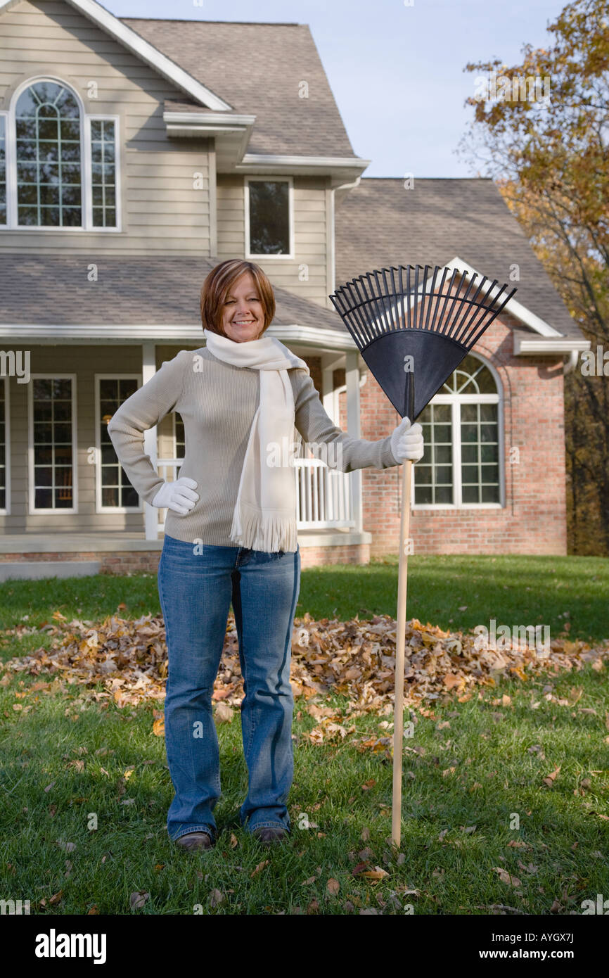 Woman holding rake in yard Stock Photo - Alamy