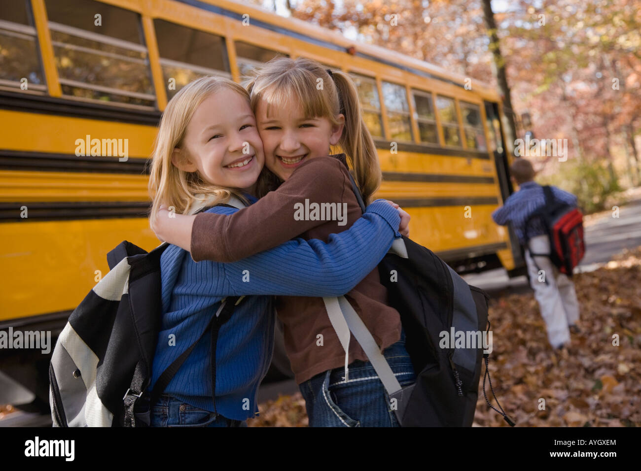 Girls hugging in front of school bus Stock Photo - Alamy