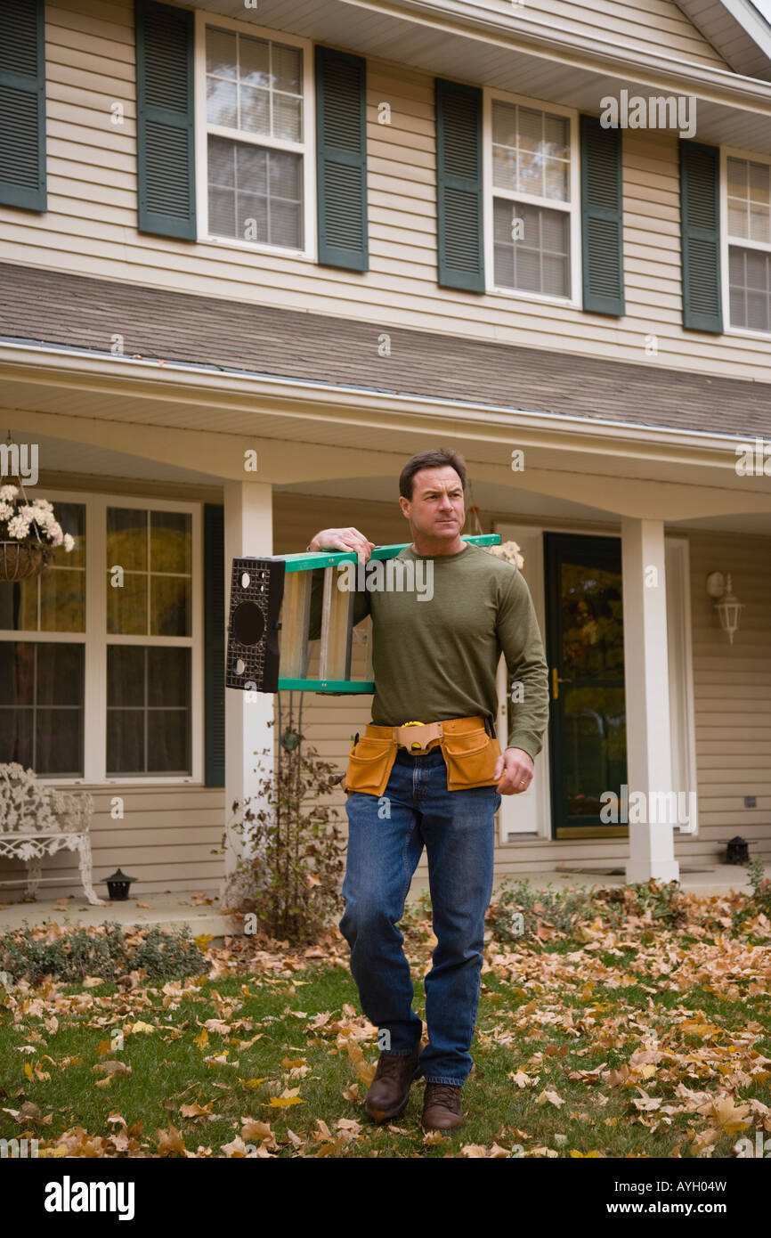 Man carrying ladder next to house Stock Photo - Alamy