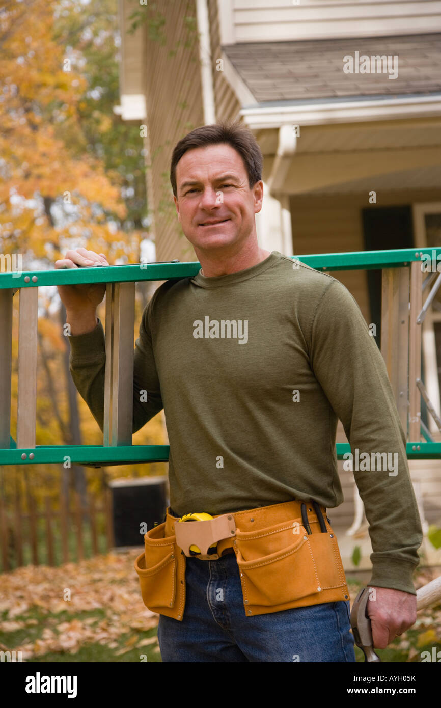 Man holding ladder next to house Stock Photo - Alamy