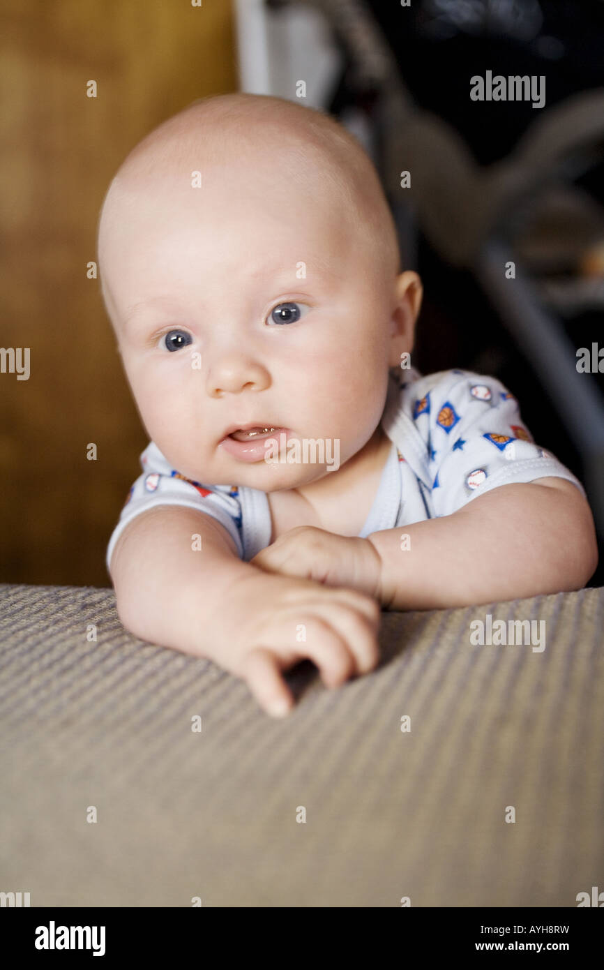 A bald baby learning to balance on a chair Stock Photo - Alamy