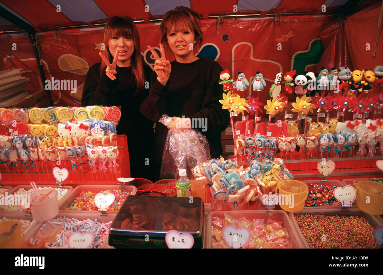 Young Japanese women selling candy from market stall at Miwa Jinja ...