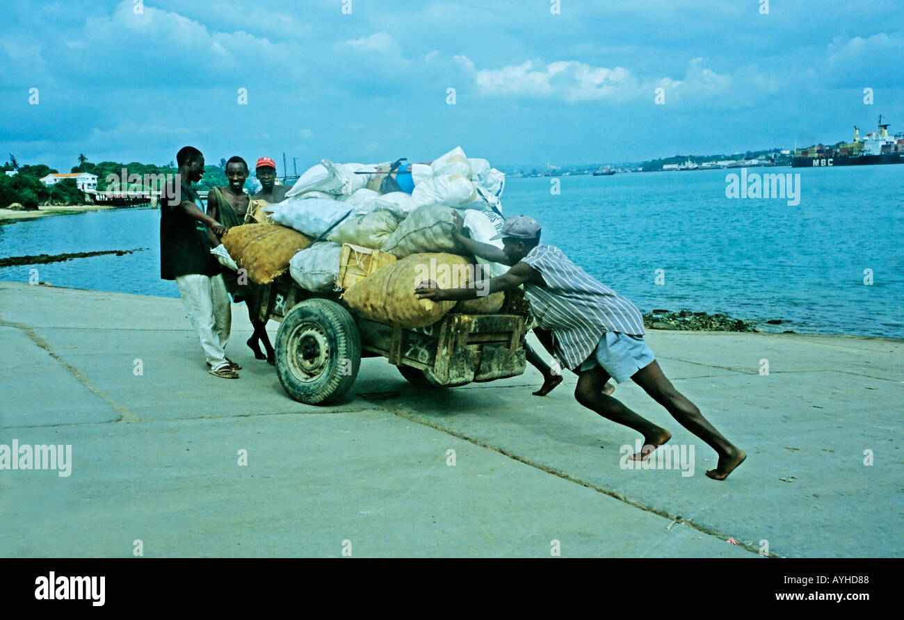 AFRICA KENYA MOMBASA Kenyan men work to push and pull cart load of ...