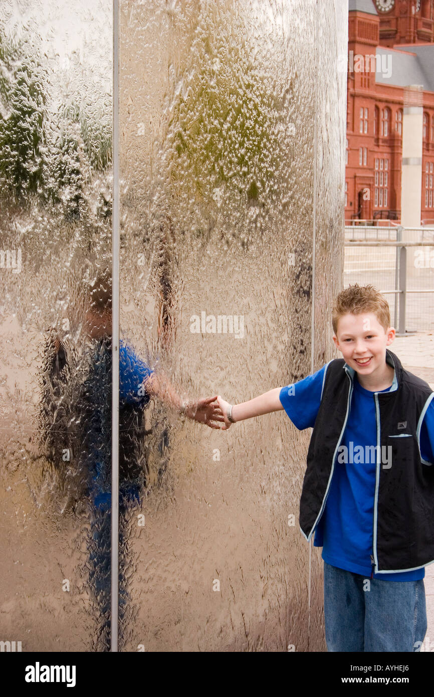 Boy running his fingers through the descending ripples of the Water ...