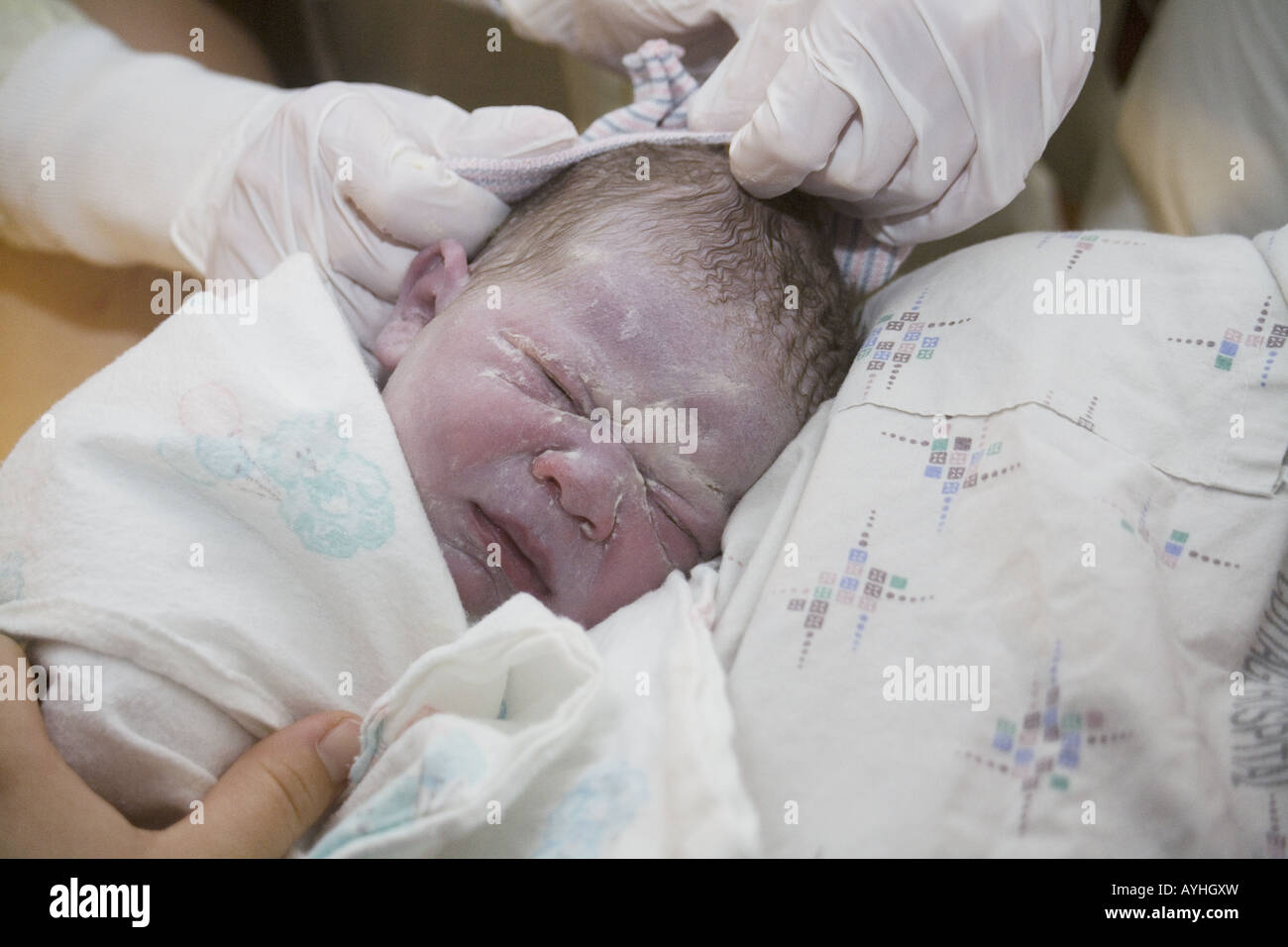 A nurse placing a cap on a newborn baby's head after childbirth Stock ...