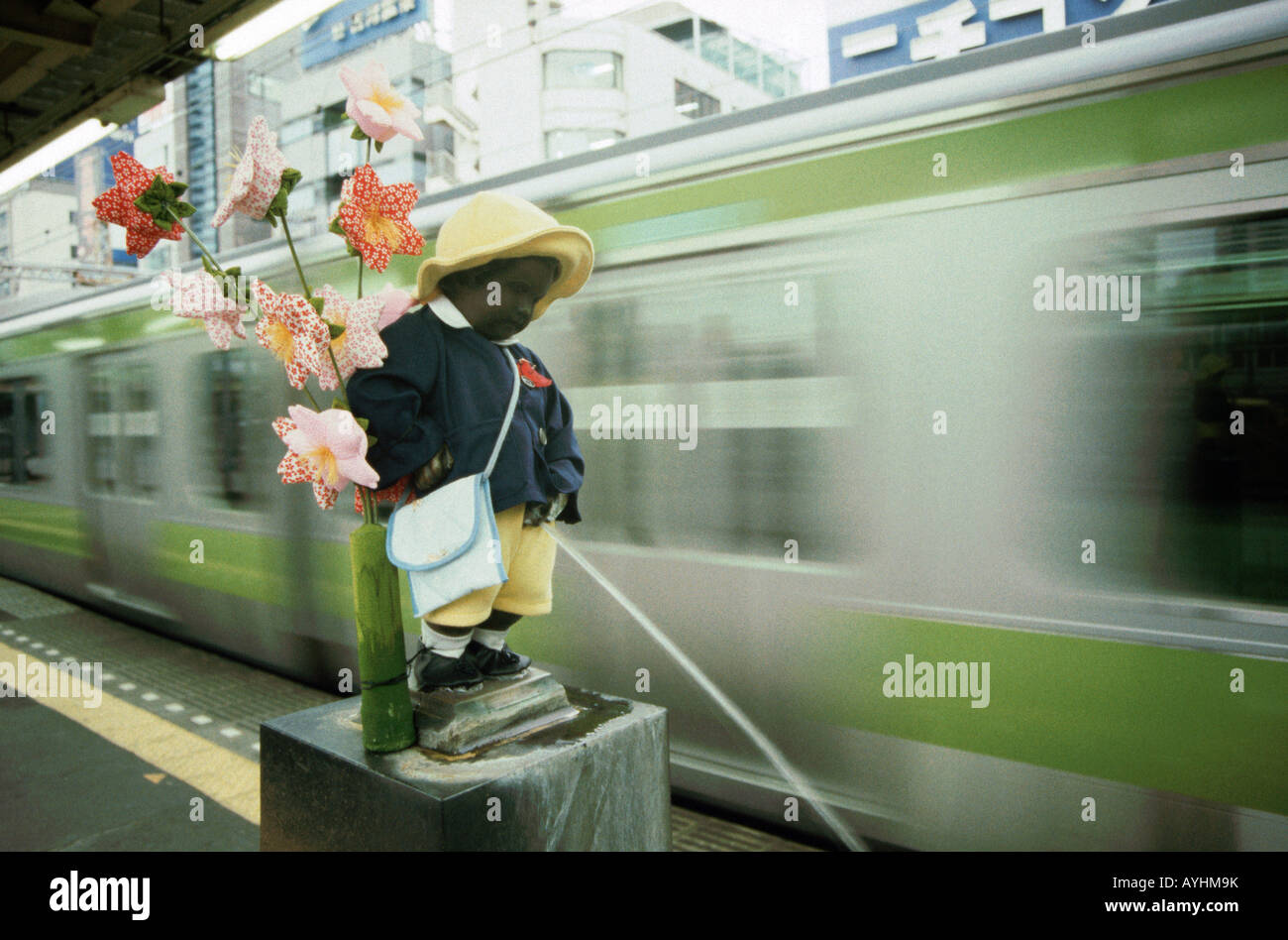 Quirky water fountain statue of urinating child against passing Japan ...