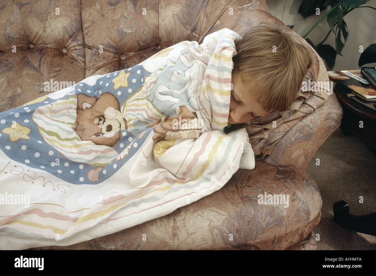 young boy ill with a cold resting on the couch under his duvet Stock ...