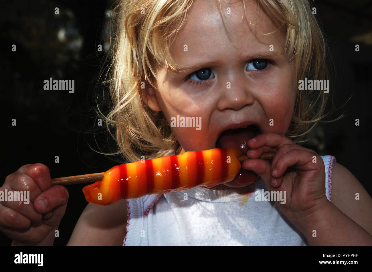 Toddler girl eating a colourfull icescream during her holidays in Spain ...