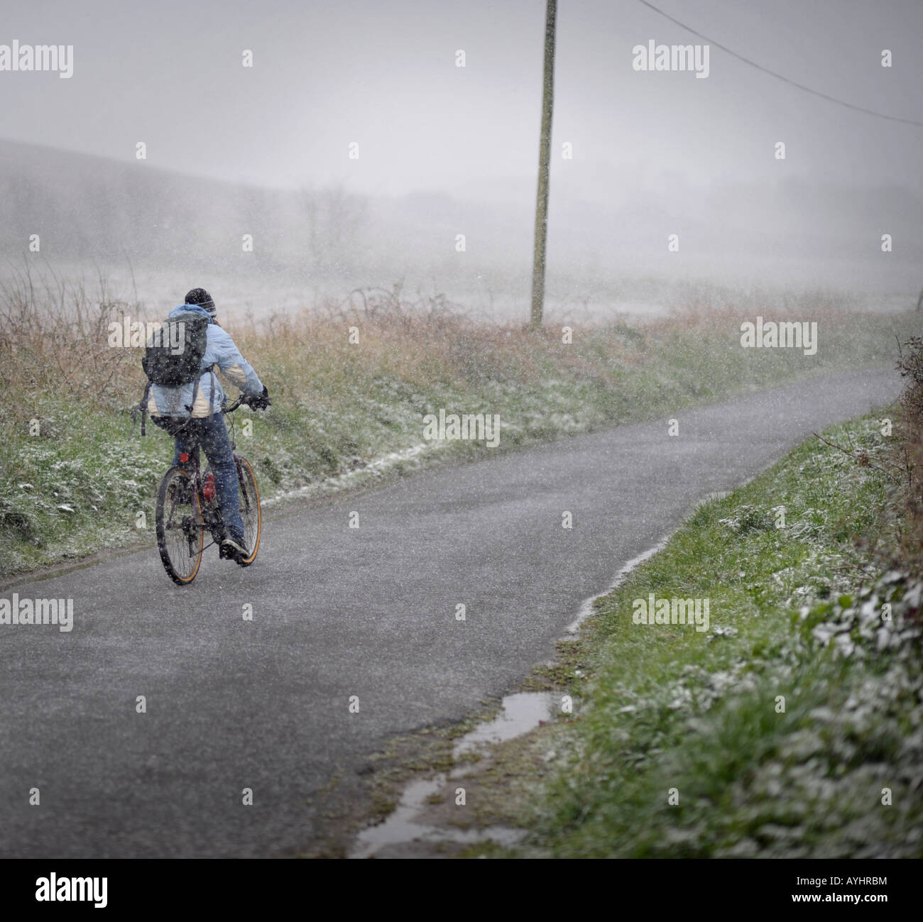 single cyclist riding in hail and sleet shower Stock Photo - Alamy