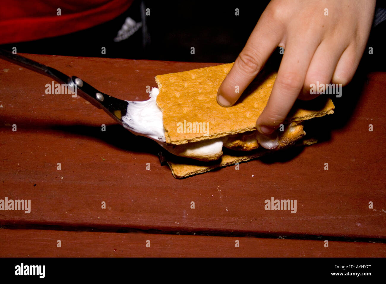 Squeezing marshmallow between two graham crackers and a slab of ...