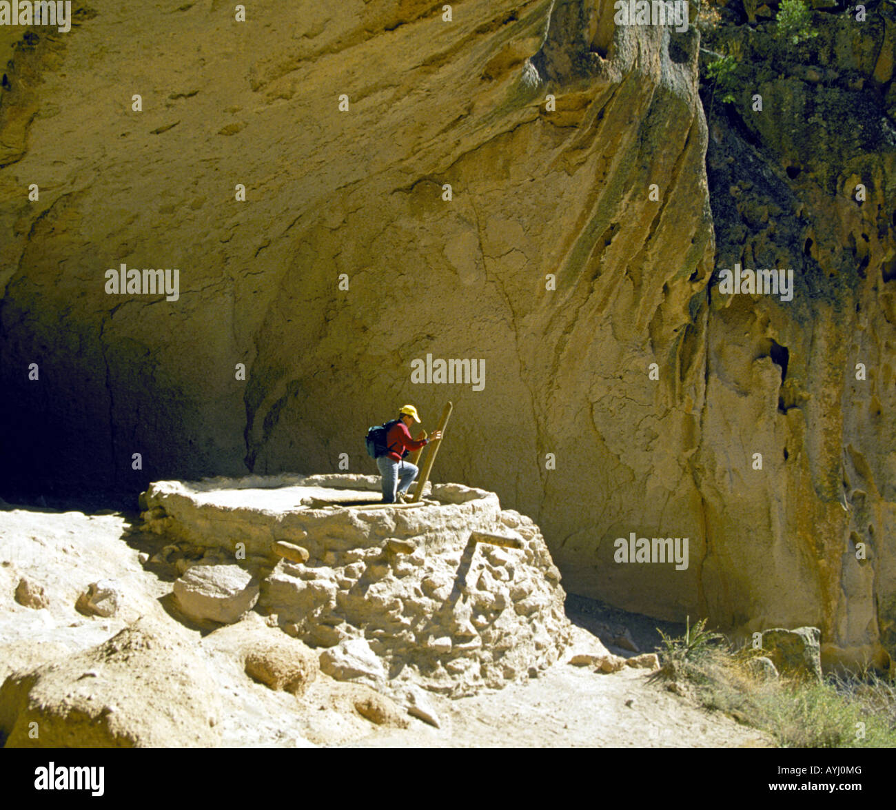 A hiker climbs into an ancient Anasazi Indian kiva or religious ...