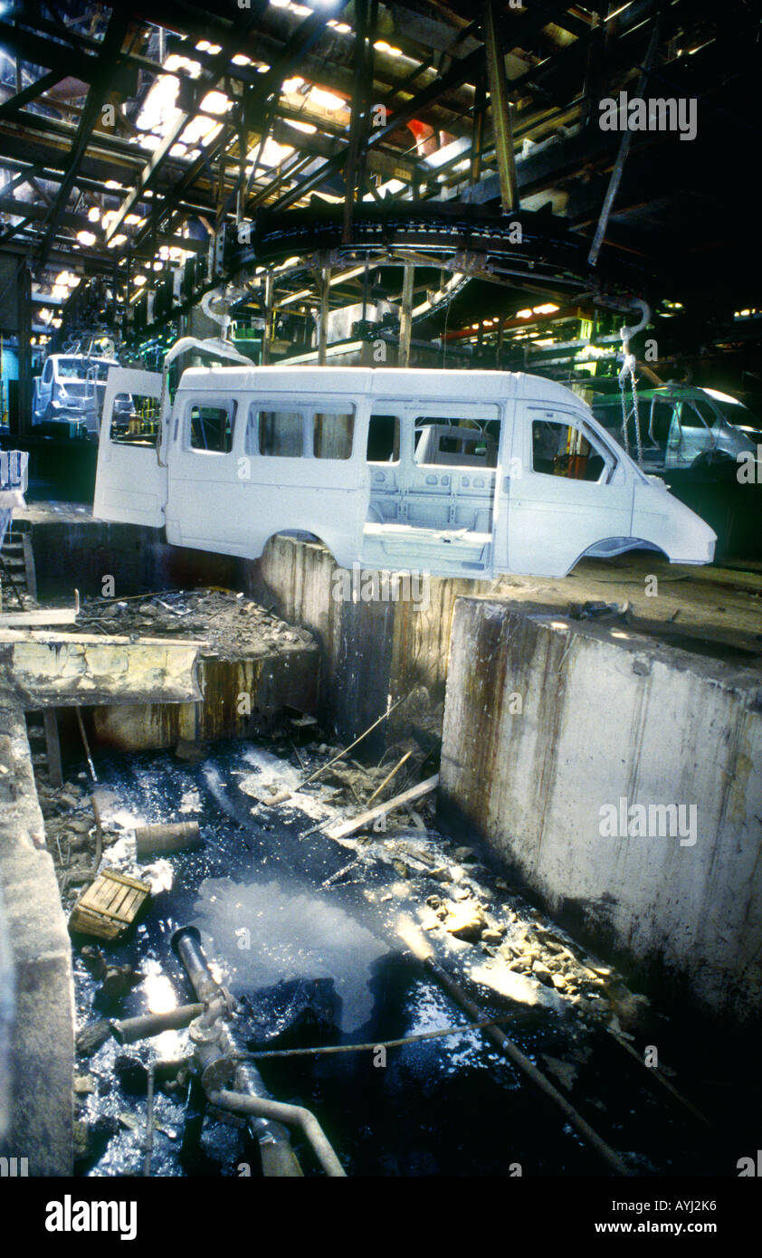 Car moving on conveyor belt factory, large pit of debris underneath ...