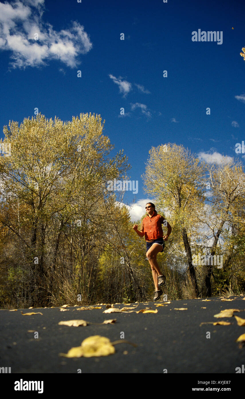 Woman running in the fall on a paved trail system in Sun Valley Idaho ...