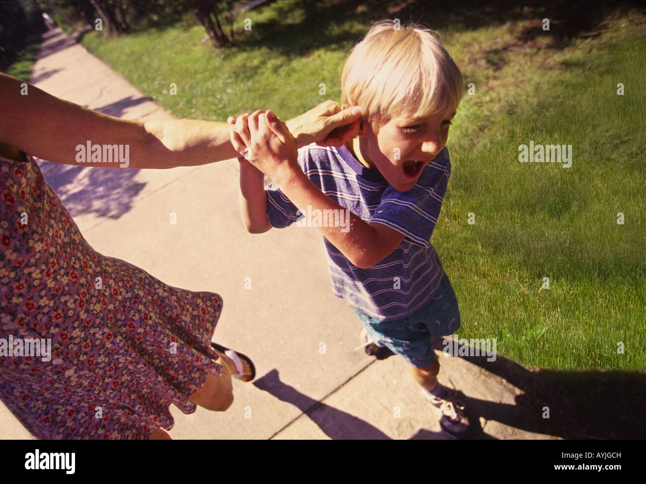 woman twisting young boy's ear while walking on sidewalk Stock Photo ...