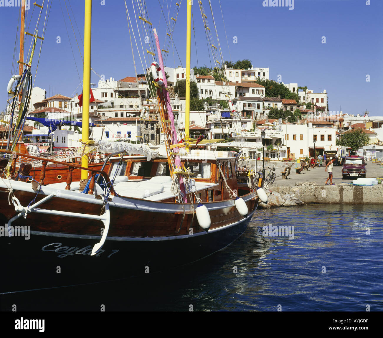 View across harbour Boats moored Tall masted gulet crusing boat Houses ...