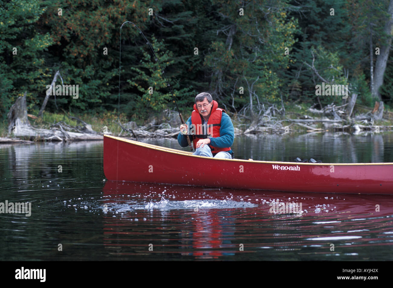 man catching fish while sitting in a canoe Stock Photo - Alamy