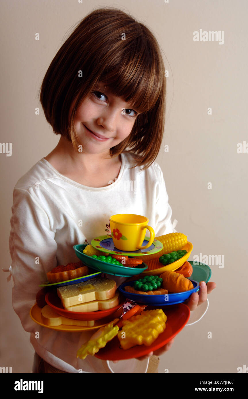 Girl carrying toy plates of food Stock Photo - Alamy