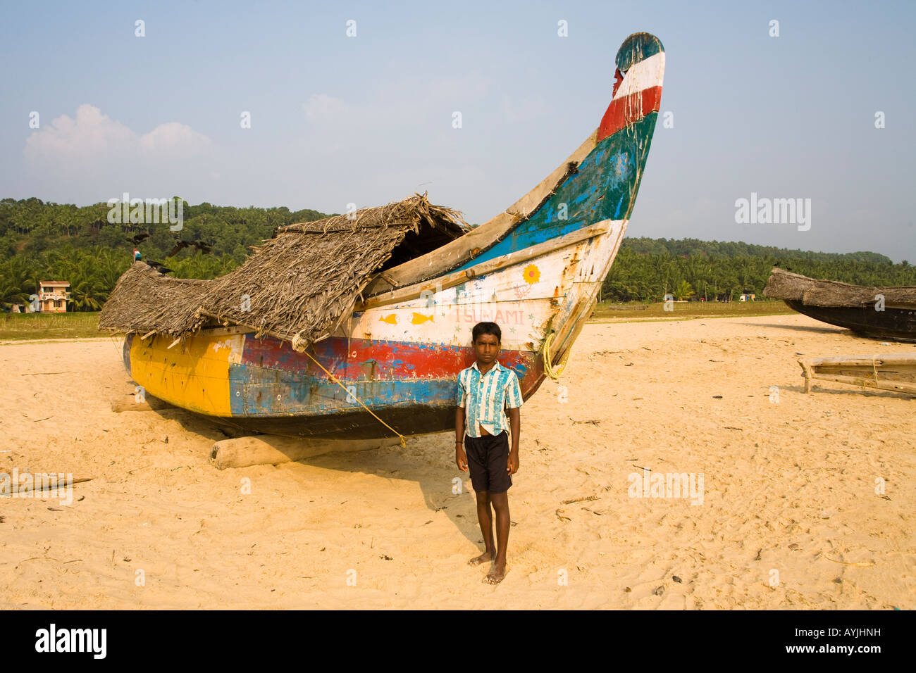 Young boy standing beside a fishing boat on Chowara Beach, Chowara ...
