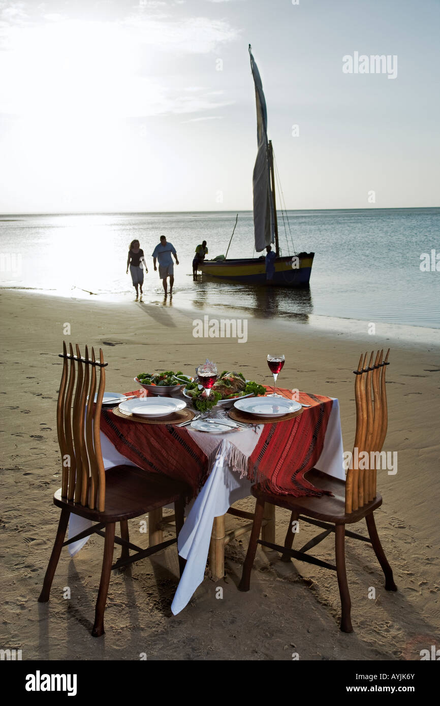 Romantic seaside fish dinner on the shore with tourists and a dhow or ...