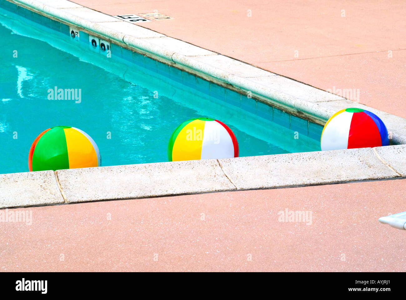 Three colorful beach balls at the end of the pool separate from each ...