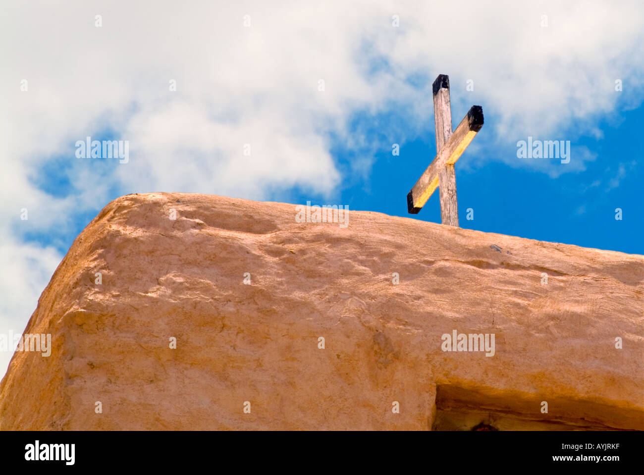 Low angle shot of cross on an adobe mission with blue sky and clouds in ...