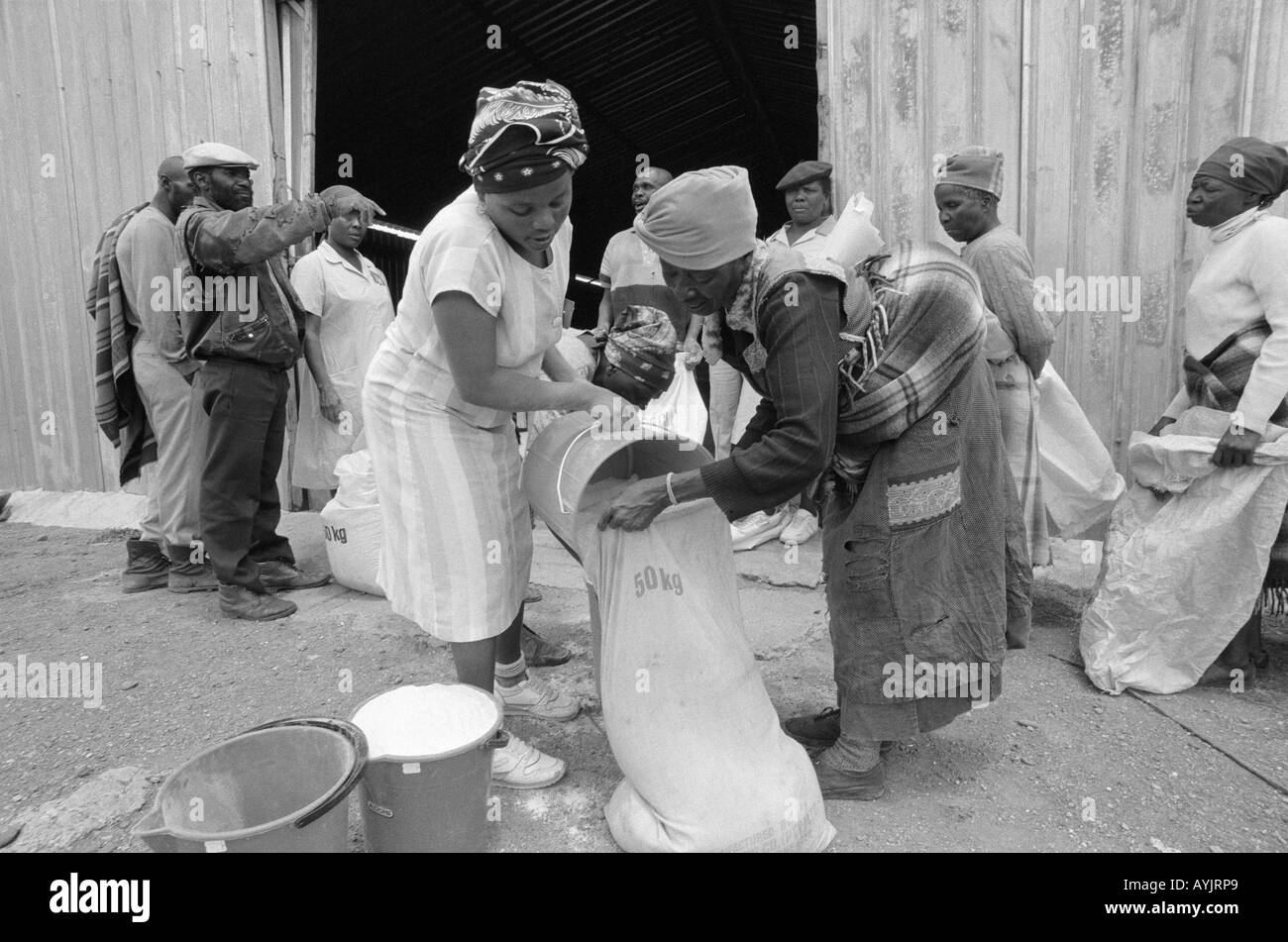 B/W of people receiving food aid of maize flour at a distribution ...