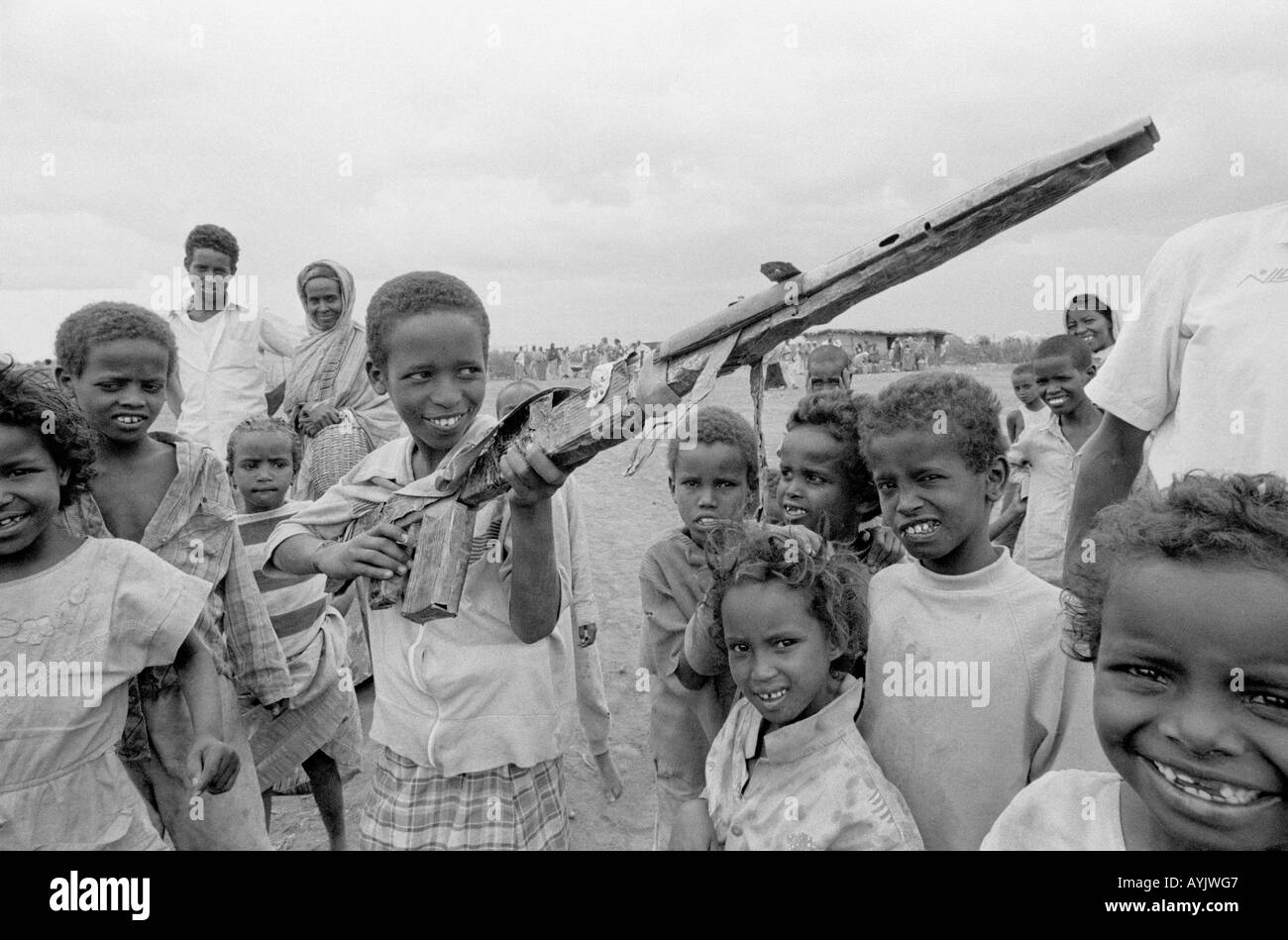 B/W of Somali refugee children playing with a homemade wooden gun at a ...
