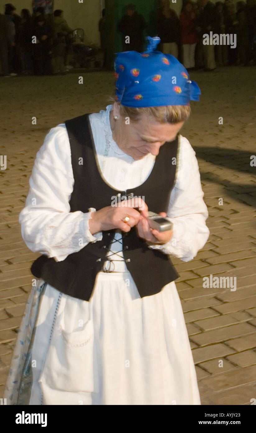 Elderly Basque woman in traditional dress checking her mobile phone ...