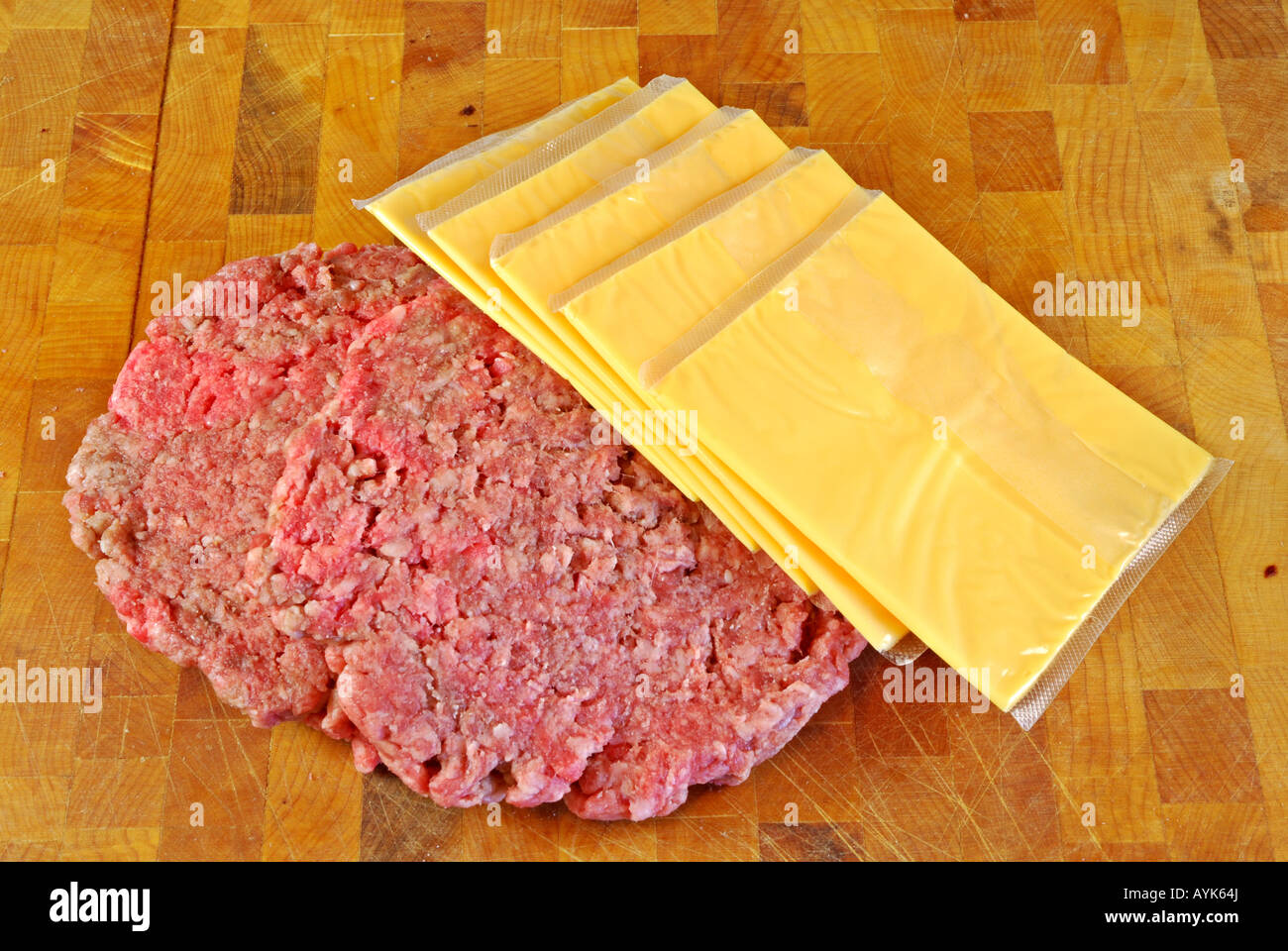 Uncooked hamburger patties with slices of American cheese Stock Photo ...