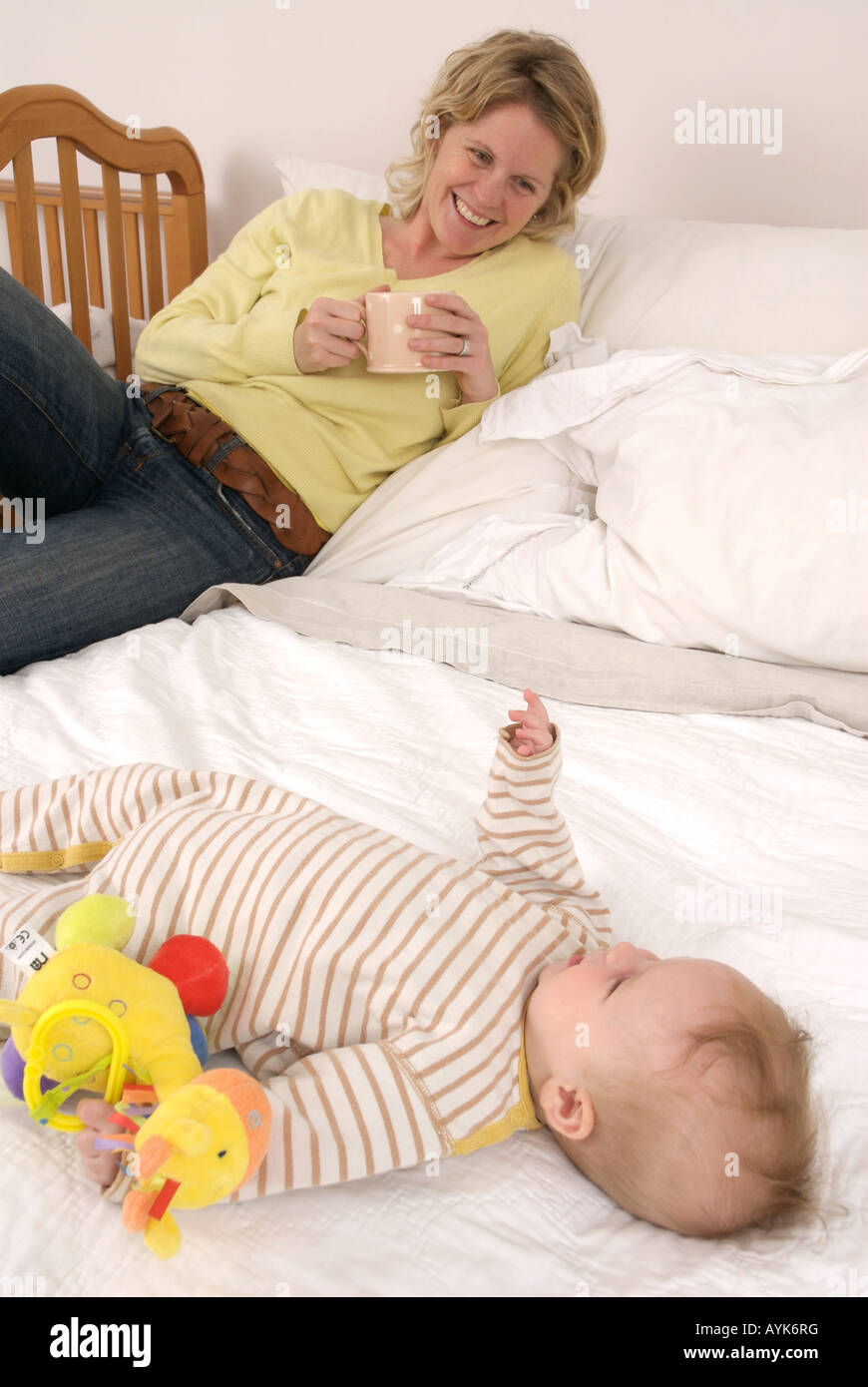 Mother watching her baby playing on the bed Stock Photo - Alamy