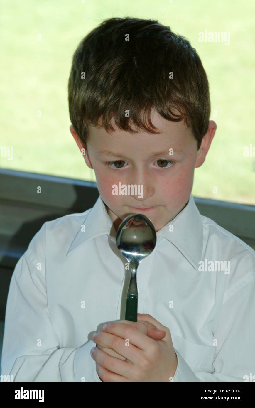 small boy looking at reflection in back of spoon Stock Photo - Alamy