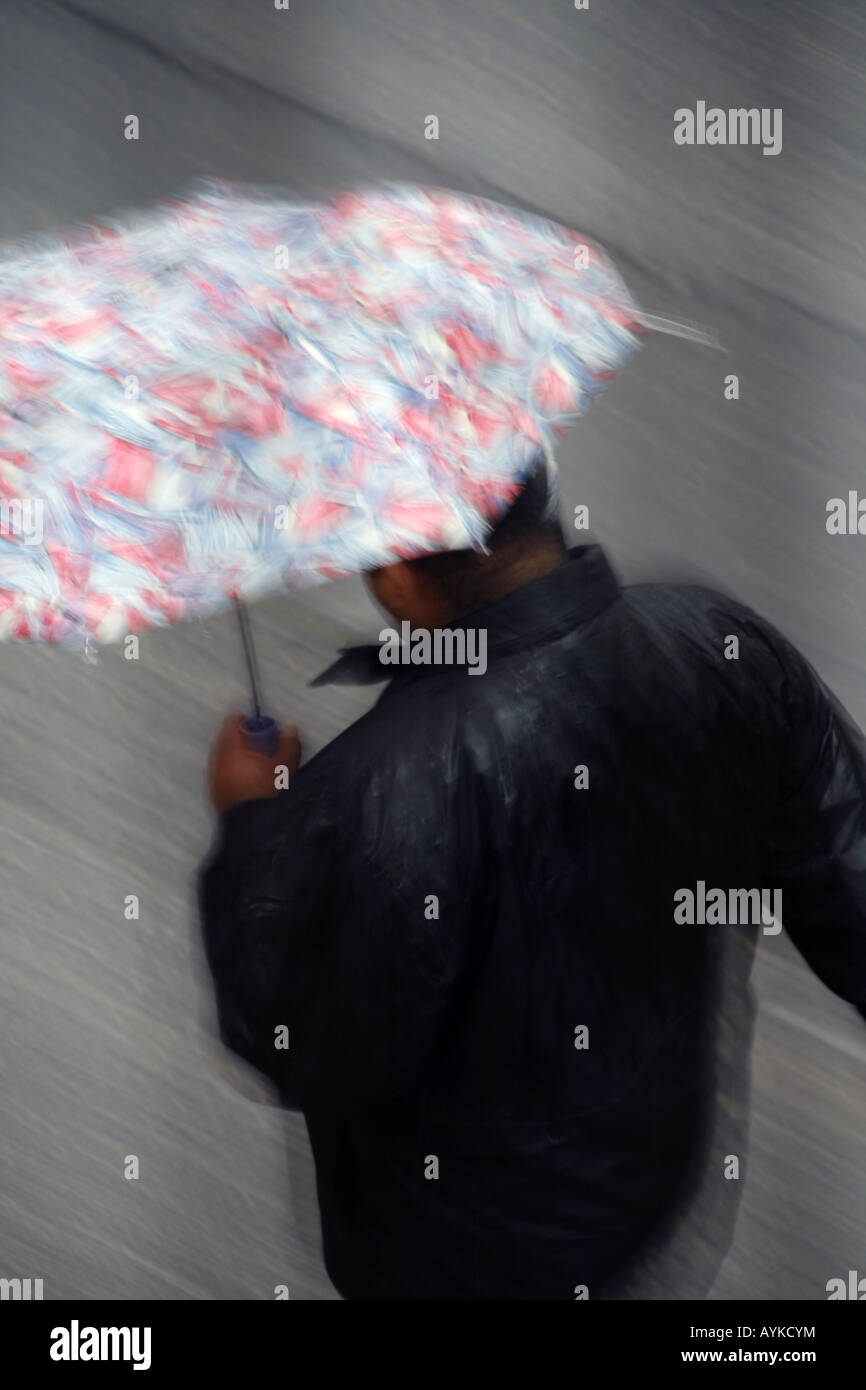 man with umbrella walking in rain in town Stock Photo - Alamy