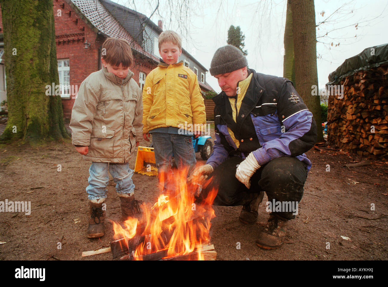 Father and sons making fire Stock Photo - Alamy