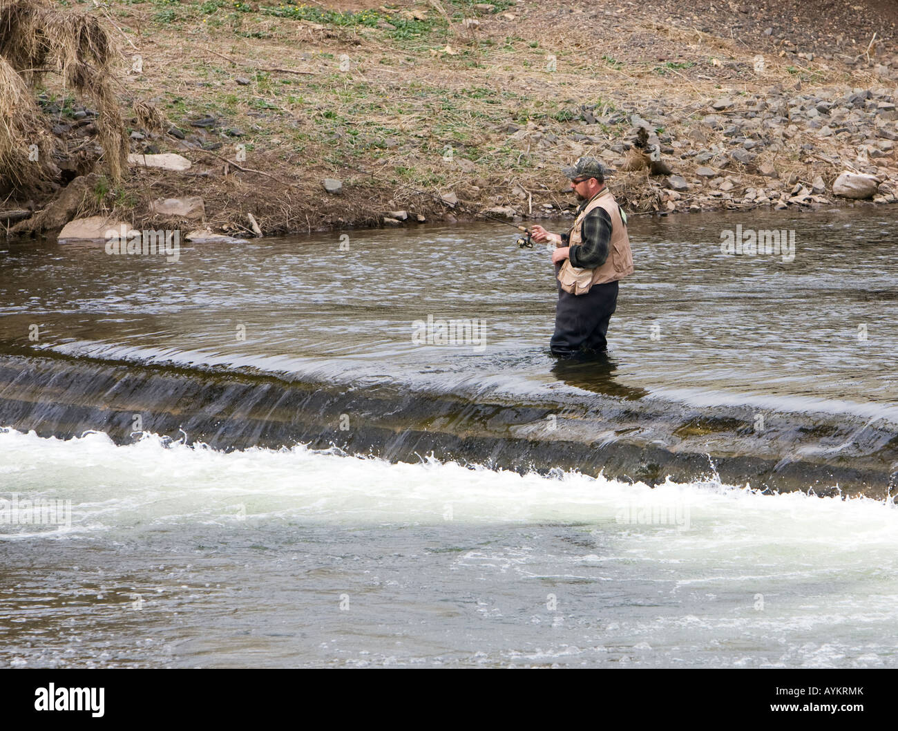 A trout fisherman standing on a small dam Stock Photo - Alamy