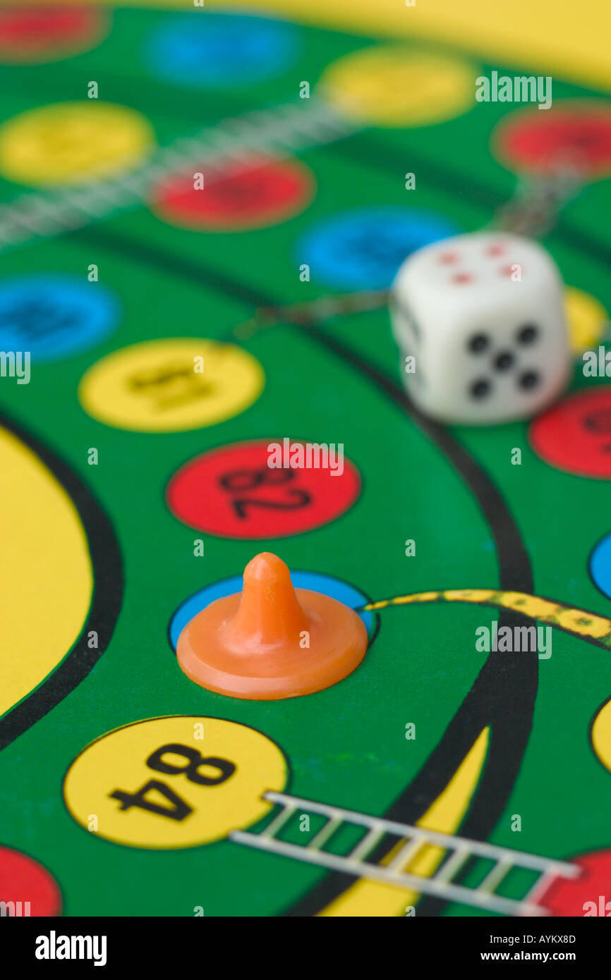 dice and piece on snakes and ladders board game Stock Photo - Alamy