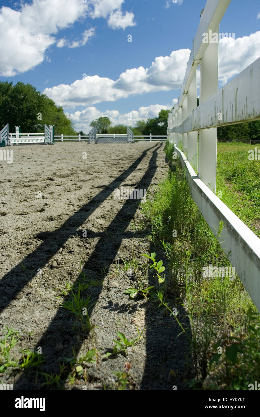 Photo of an outdoor riding arena with fence on the right and blue sky ...