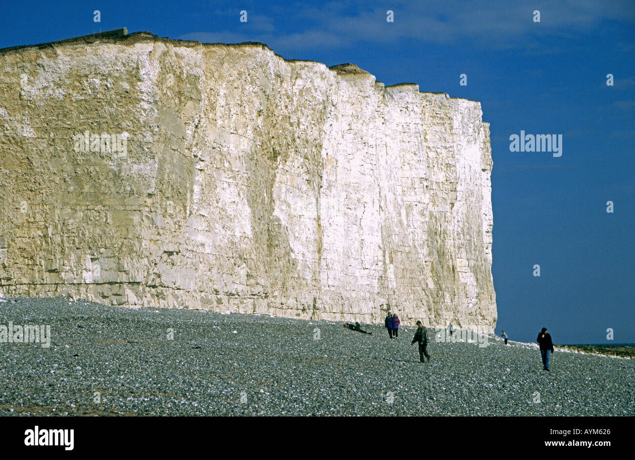 People walking on the beach below white cliffs of Beachy Head Sussex ...