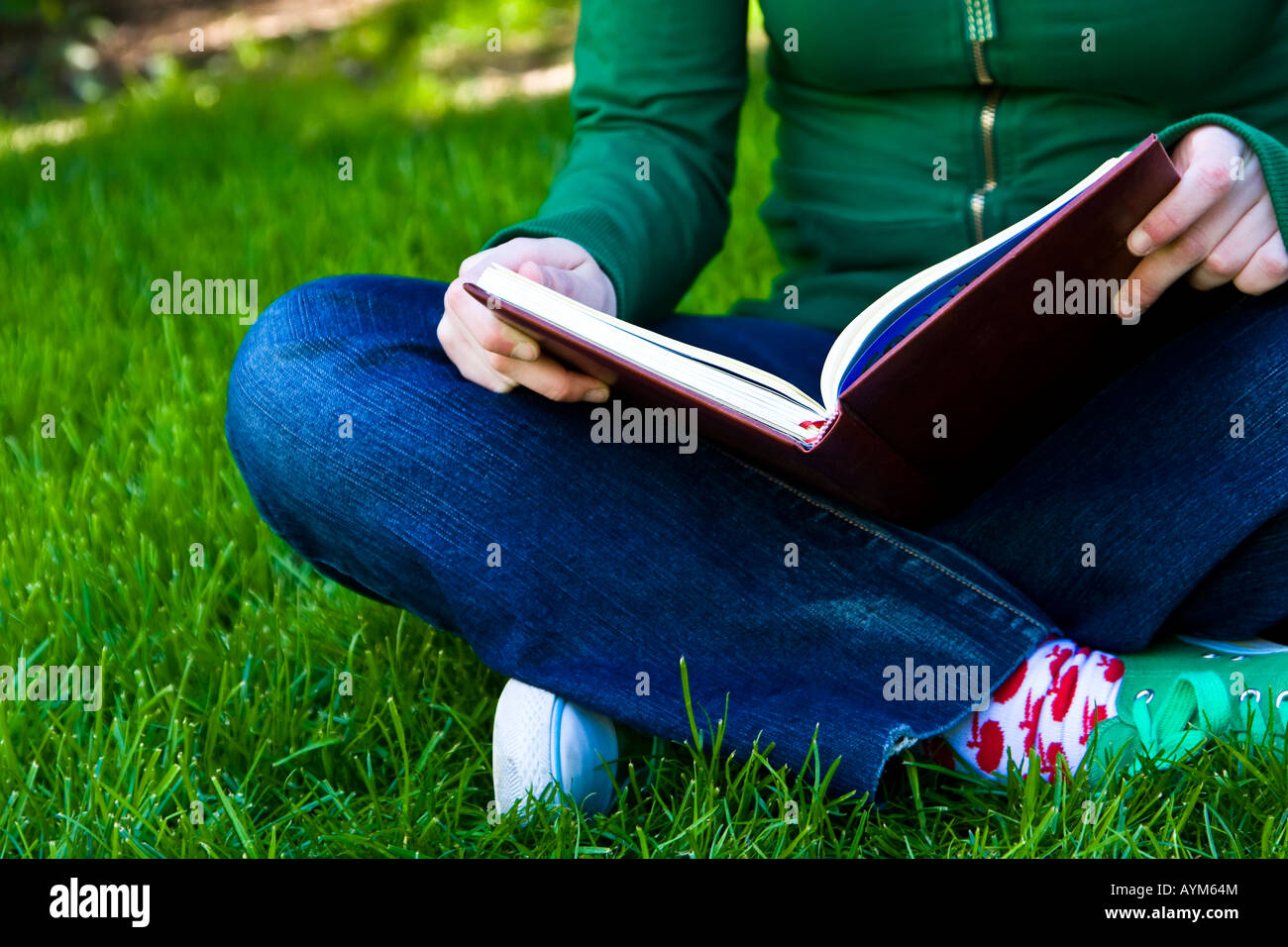 Young female student reading on the grass Stock Photo - Alamy