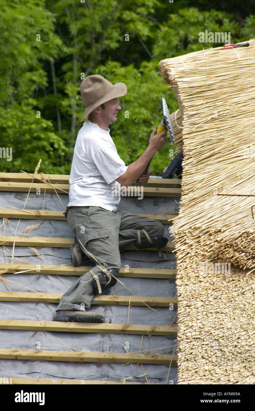 Male thatcher with hat working on a thatched roof in Co Mayo Ireland ...