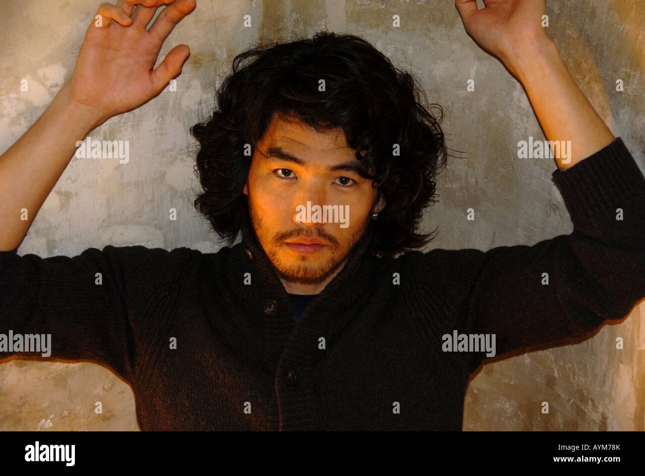 Hip Japanese male with his arms thrown over his shoulders in mock ...