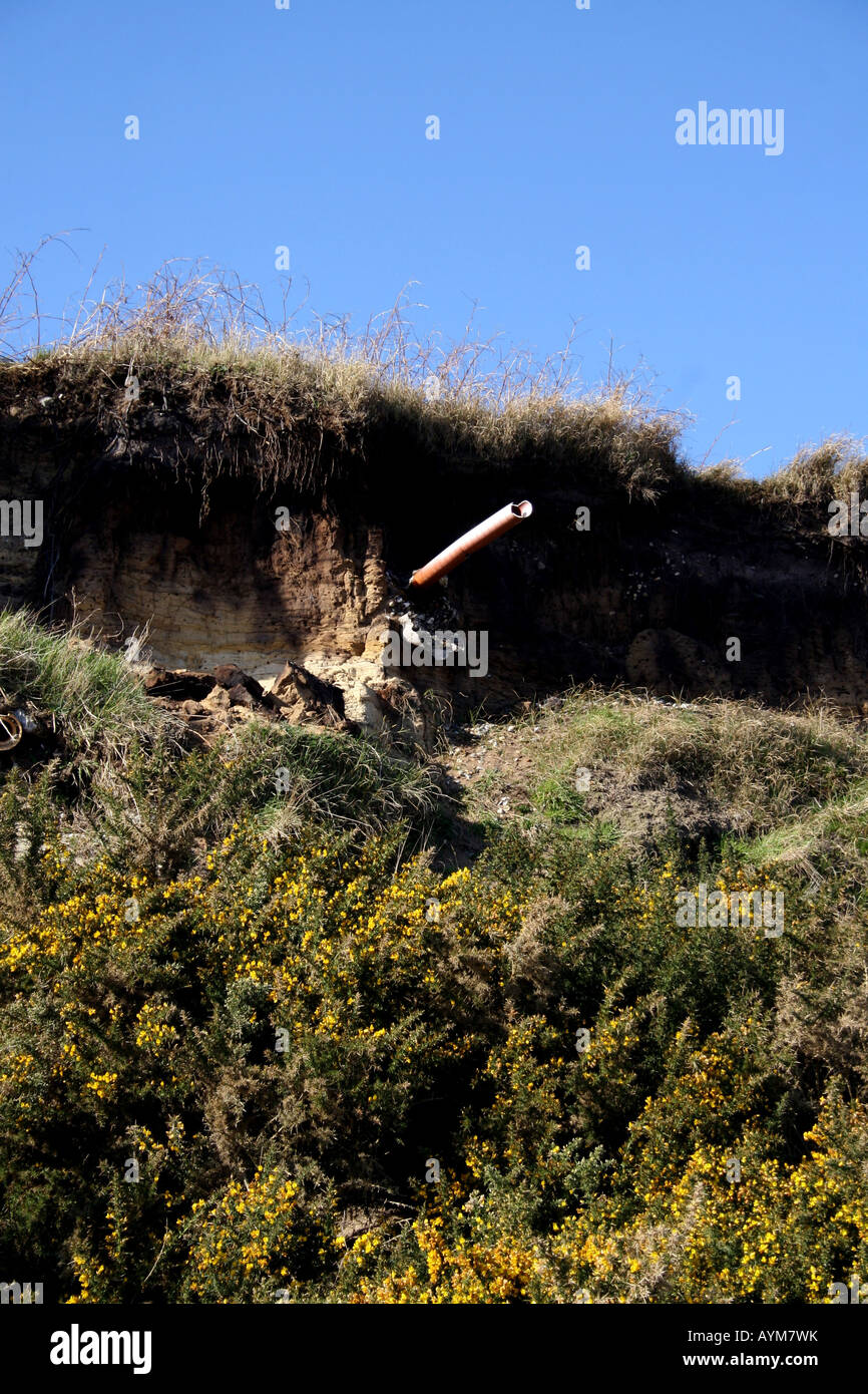 A ONCE BURIED PIPE EXTENDS FROM THE ERODED CLIFF FACE AT DUNWICH ...