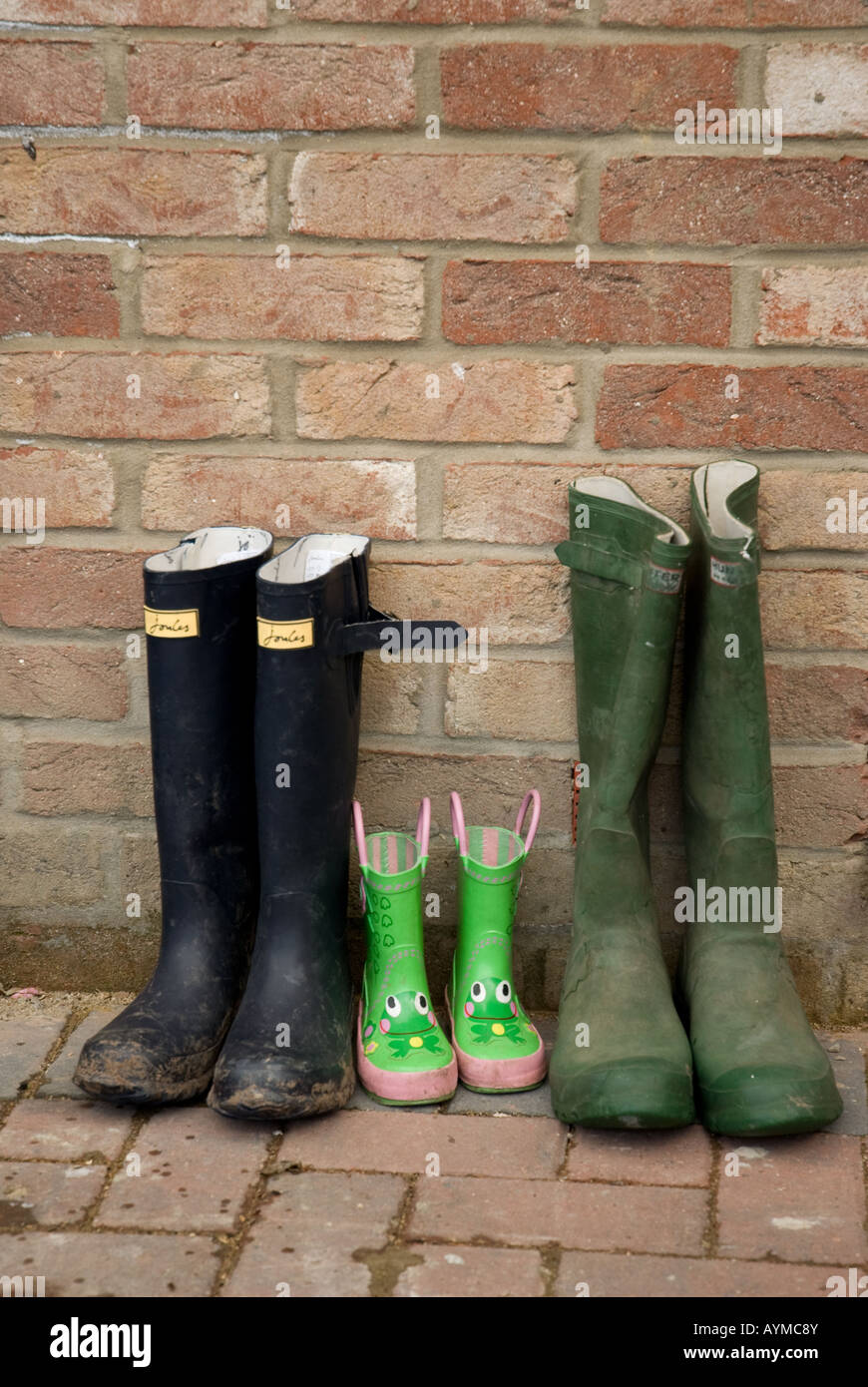 three pairs of wellies against a brick wall Stock Photo - Alamy